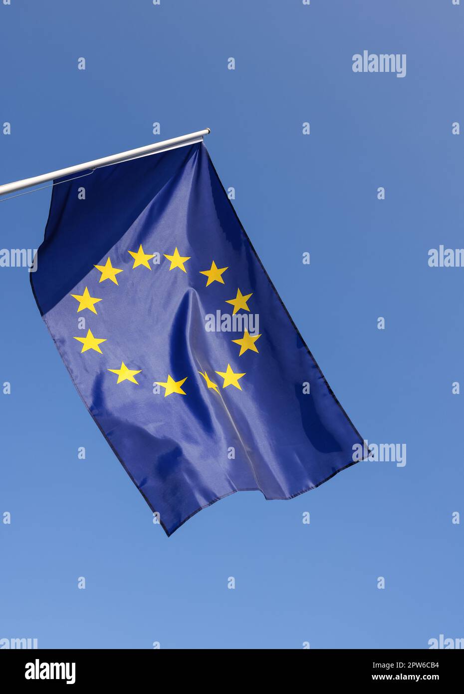 European Union EU flag hanging on flagstaff over clear blue sky, symbol ...