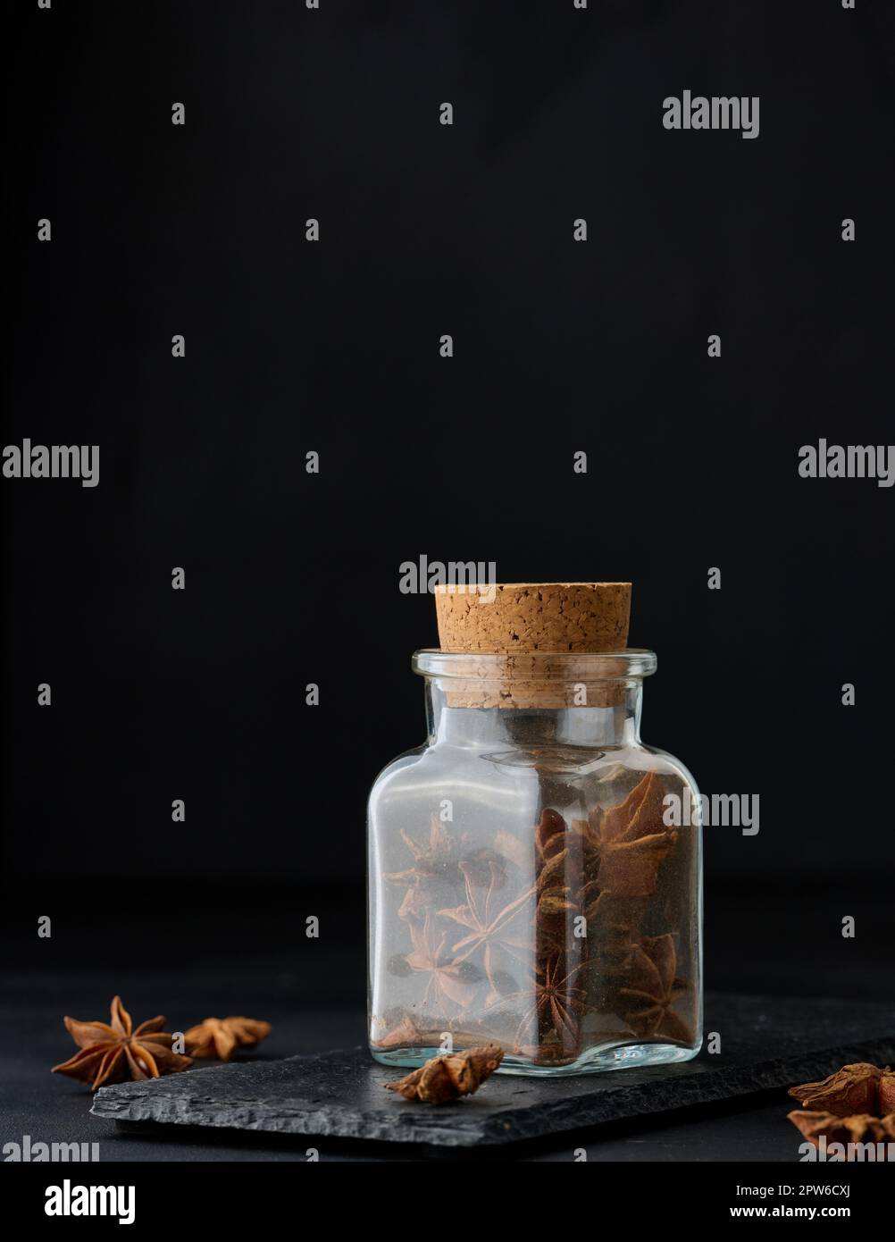Dry star anise in a transparent glass bottle on a black background ...
