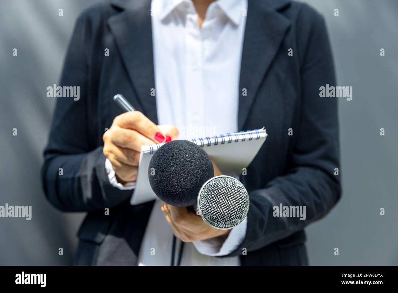 Female reporter at press conference or media event, writing notes ...