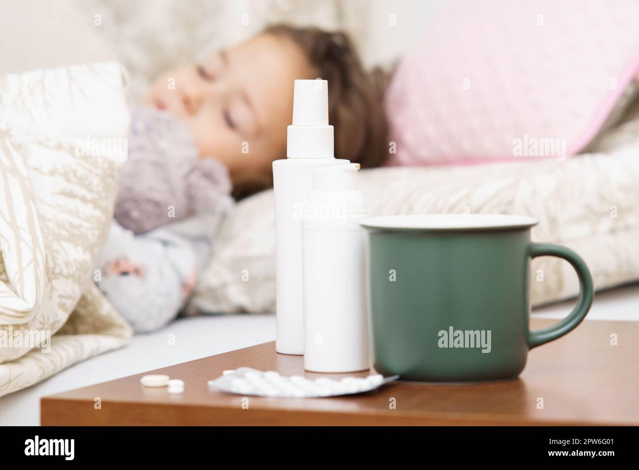 Close up green mug, nasal and throat sprays containers and pills ...