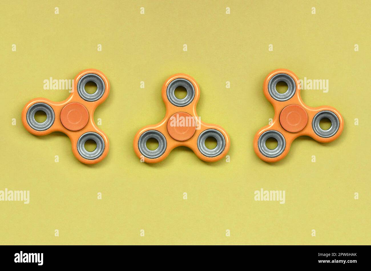 Many orange fidget spinners lies on texture background of fashion ...