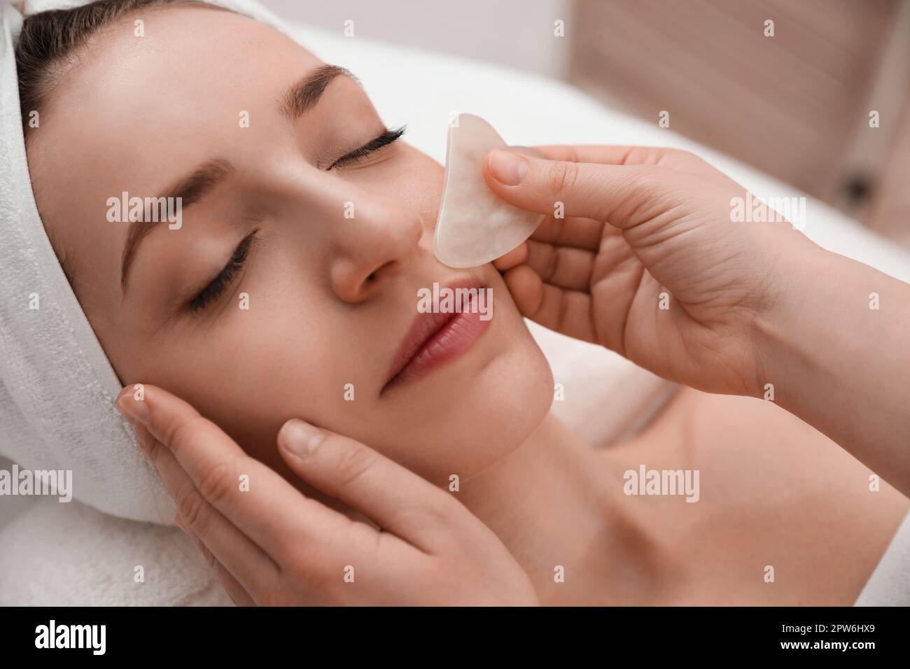 Young woman receiving facial massage with gua sha tool in beauty salon, closeup Stock Photo - Alamy