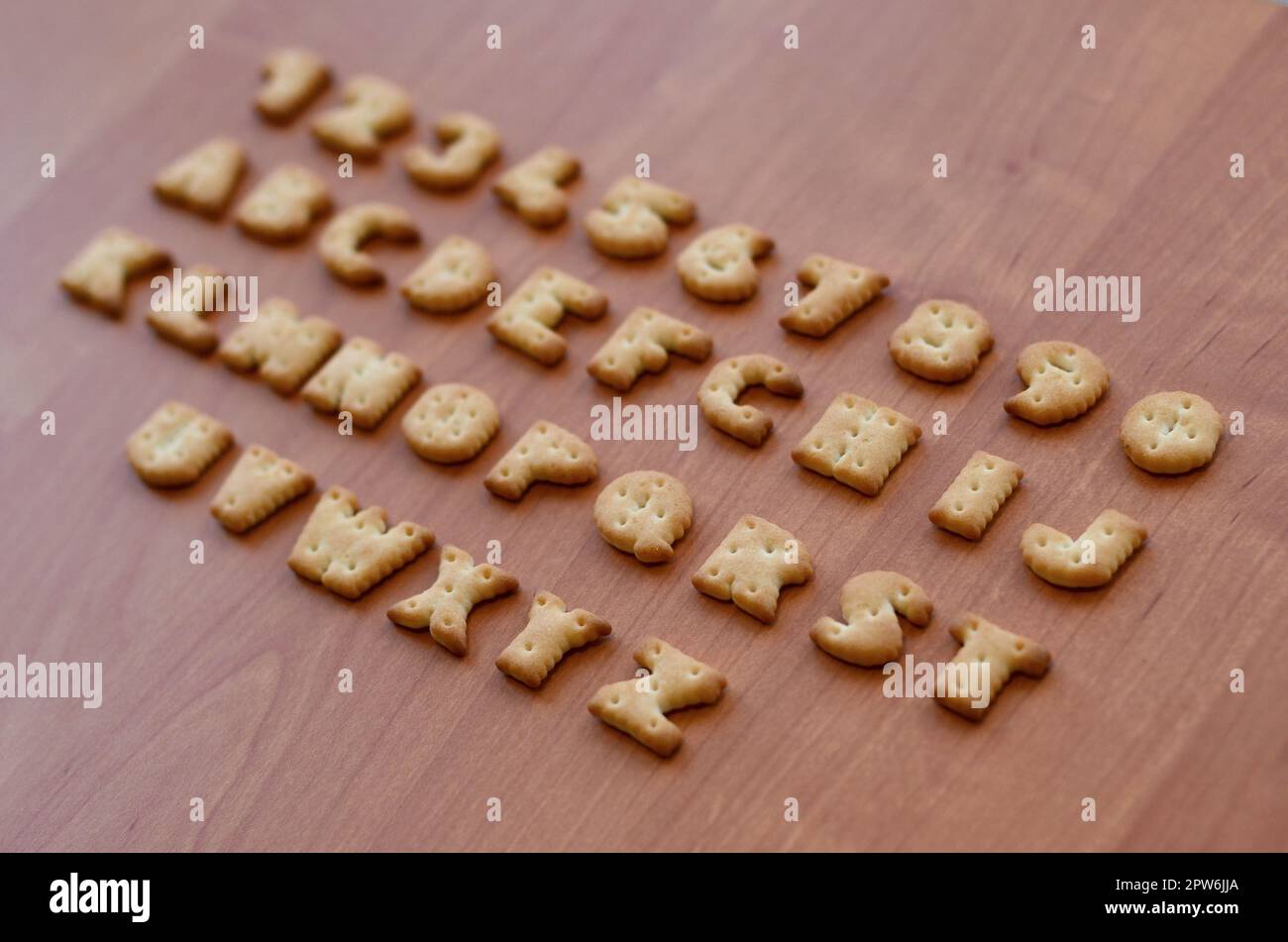 Letters of salty crackers lay on a wooden brown surface in the order ...