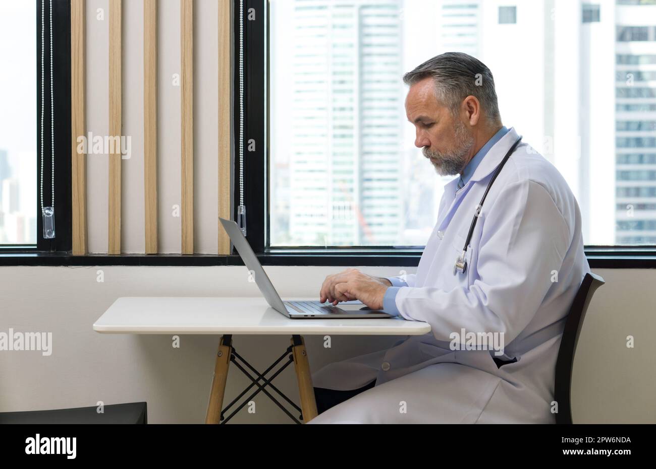 Senior professor with mustache and beard typing on laptop computer ...
