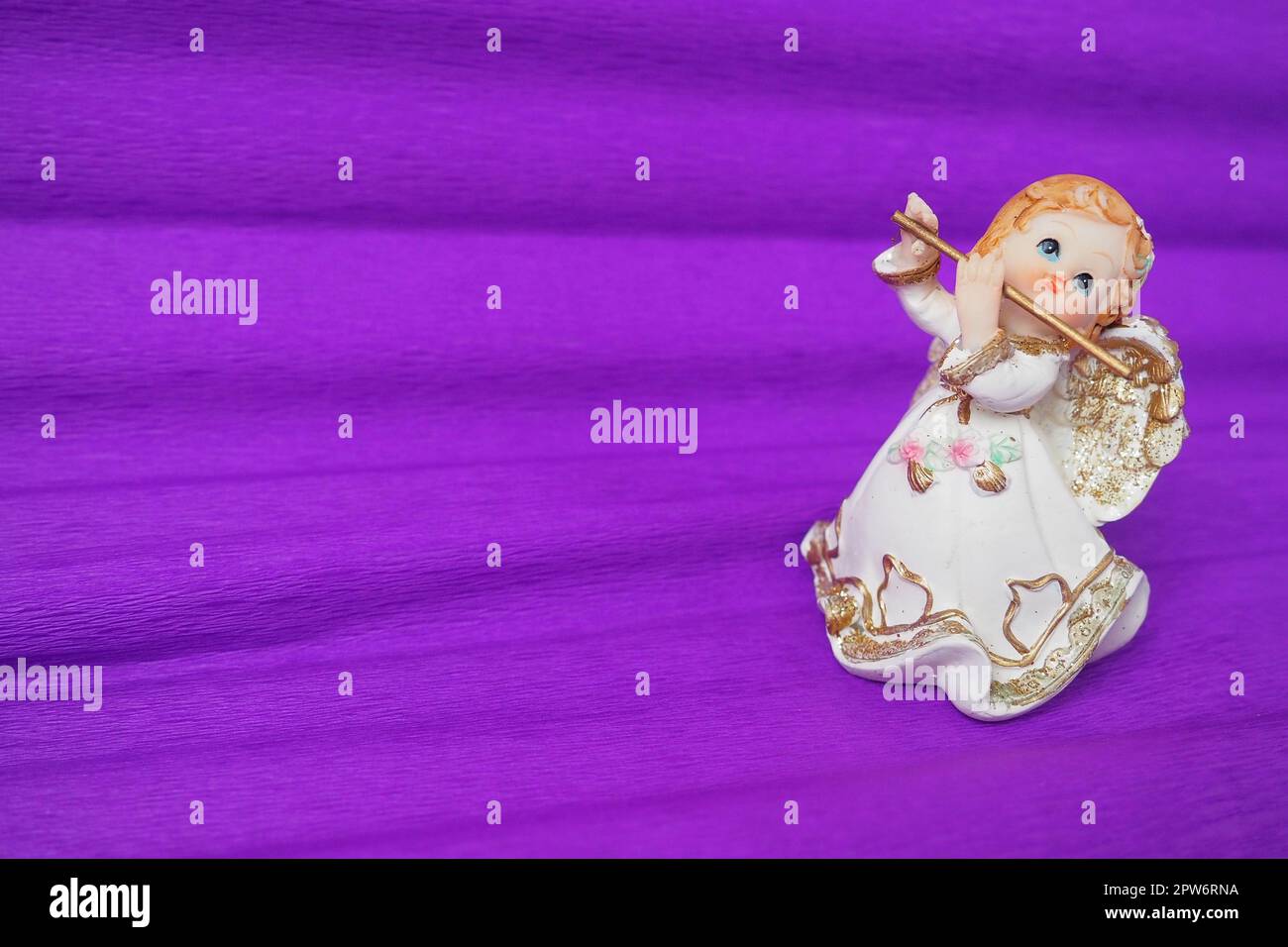 Guardian angel plays the flute. Figurine of a red-haired girl in a ...