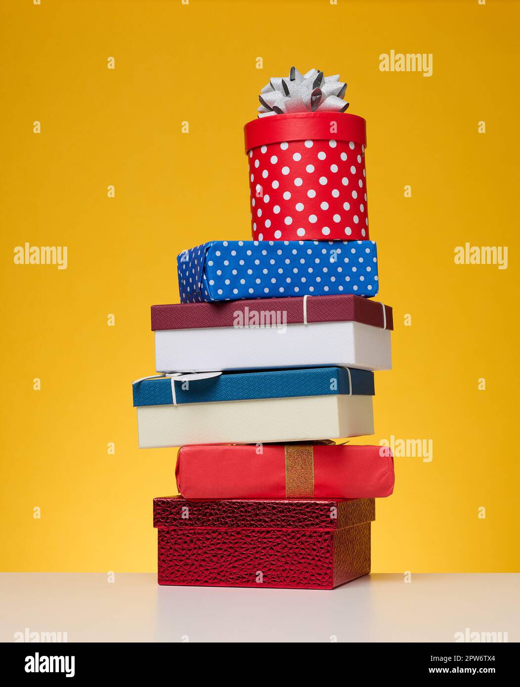 A stack of gift boxes wrapped in colorful paper on a yellow background ...