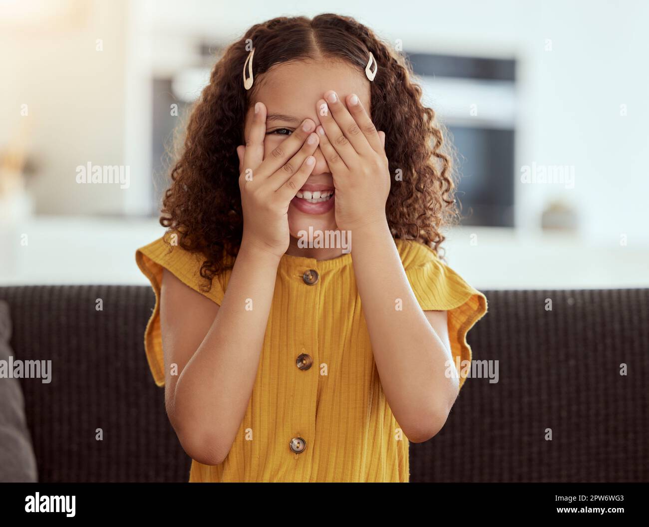 Adorable little mixed race child covering face with hands and peeking ...