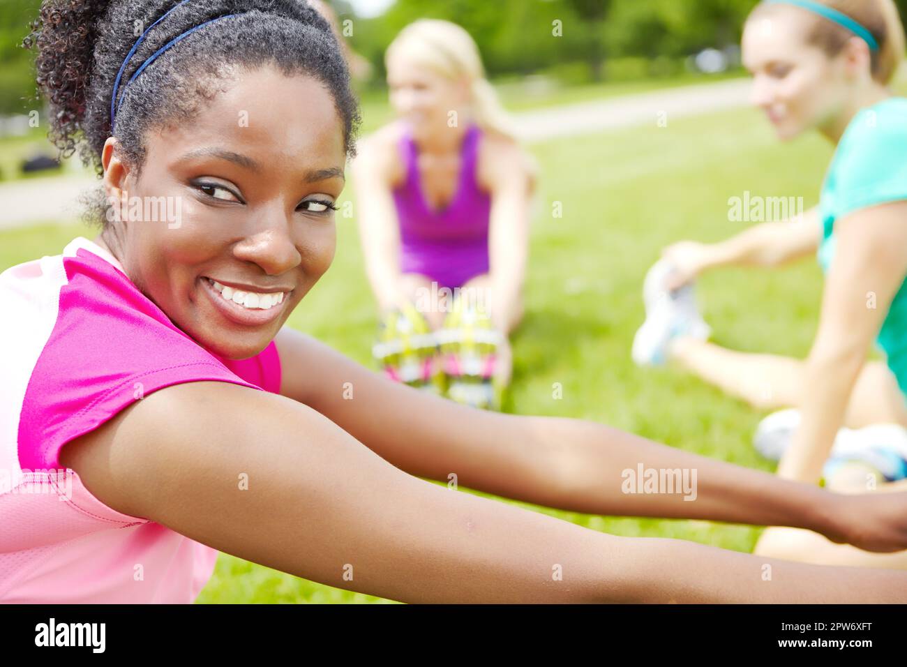 Stretching together. Side view of a female athlete looking over her ...