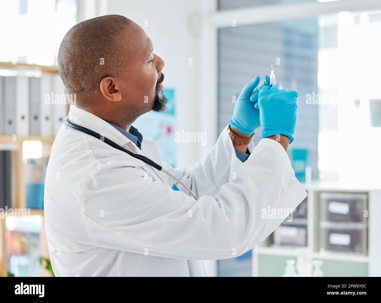 Mature doctor preparing a needle for injection. African american doctor ...