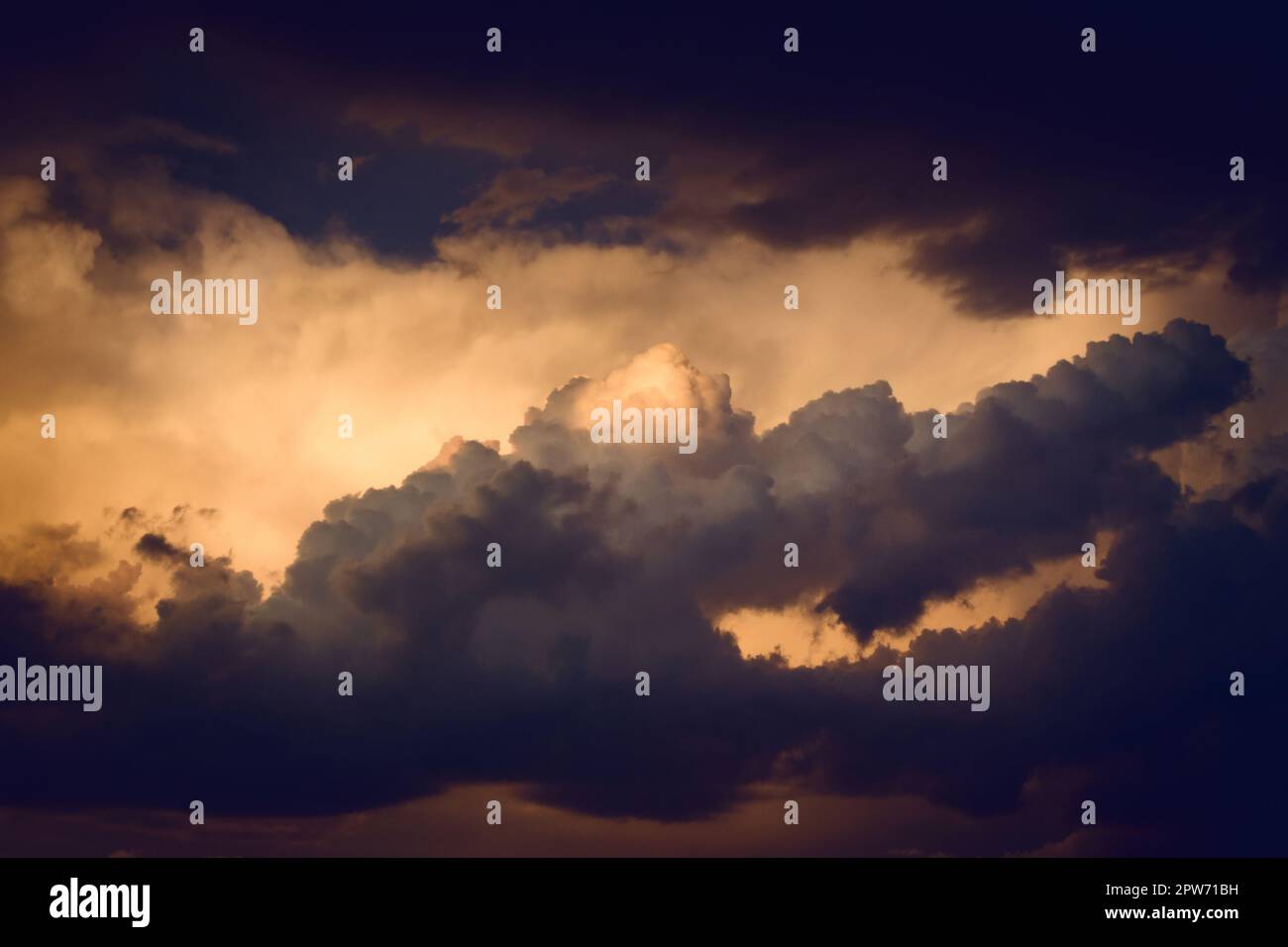Dark, dramatic nimbus clouds at sunset, lit by the last rays of ...