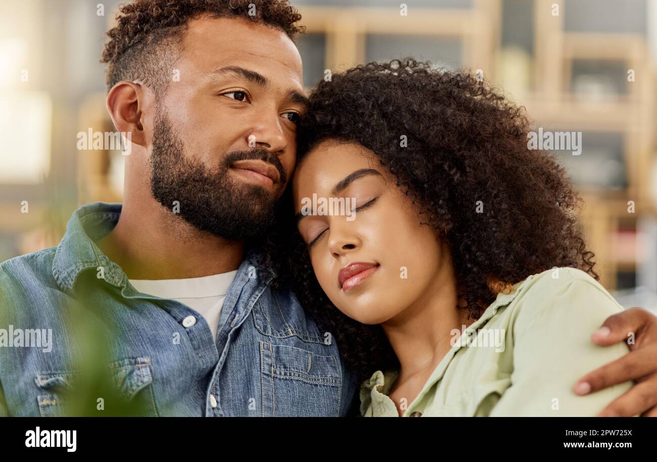 Young mixed race couple embracing while resting on the couch at home ...