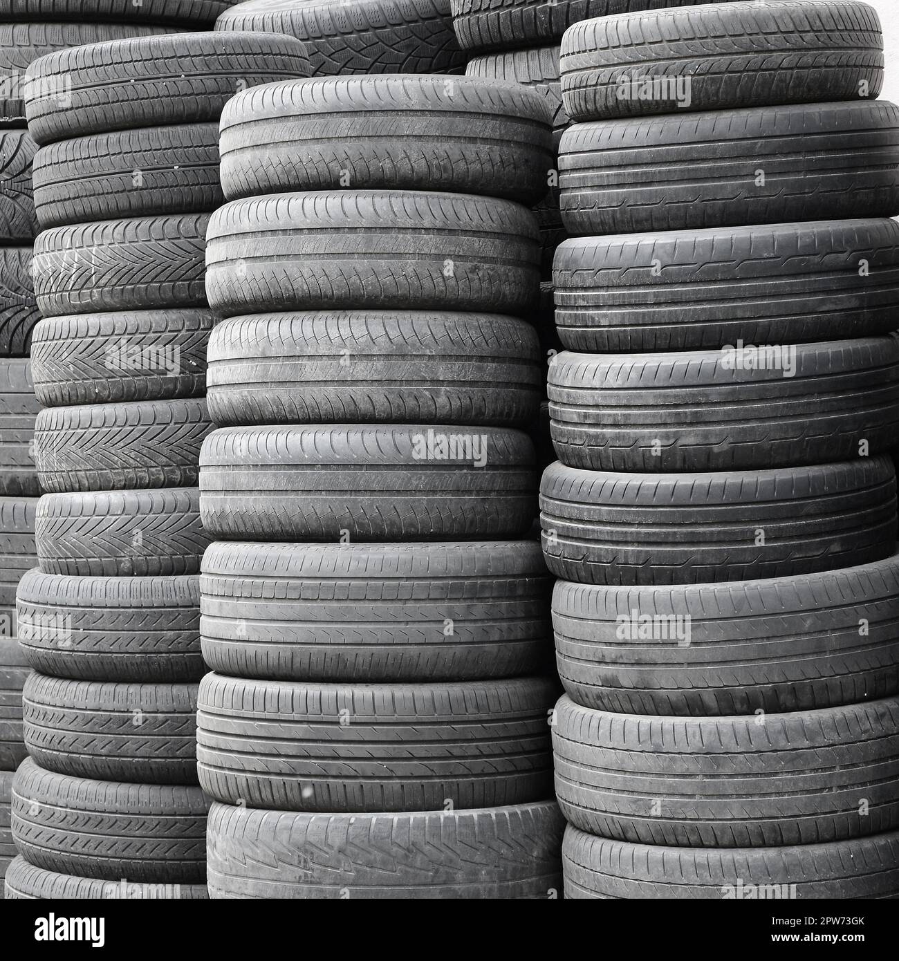 Old used tires stacked with high piles in secondary car parts shop ...
