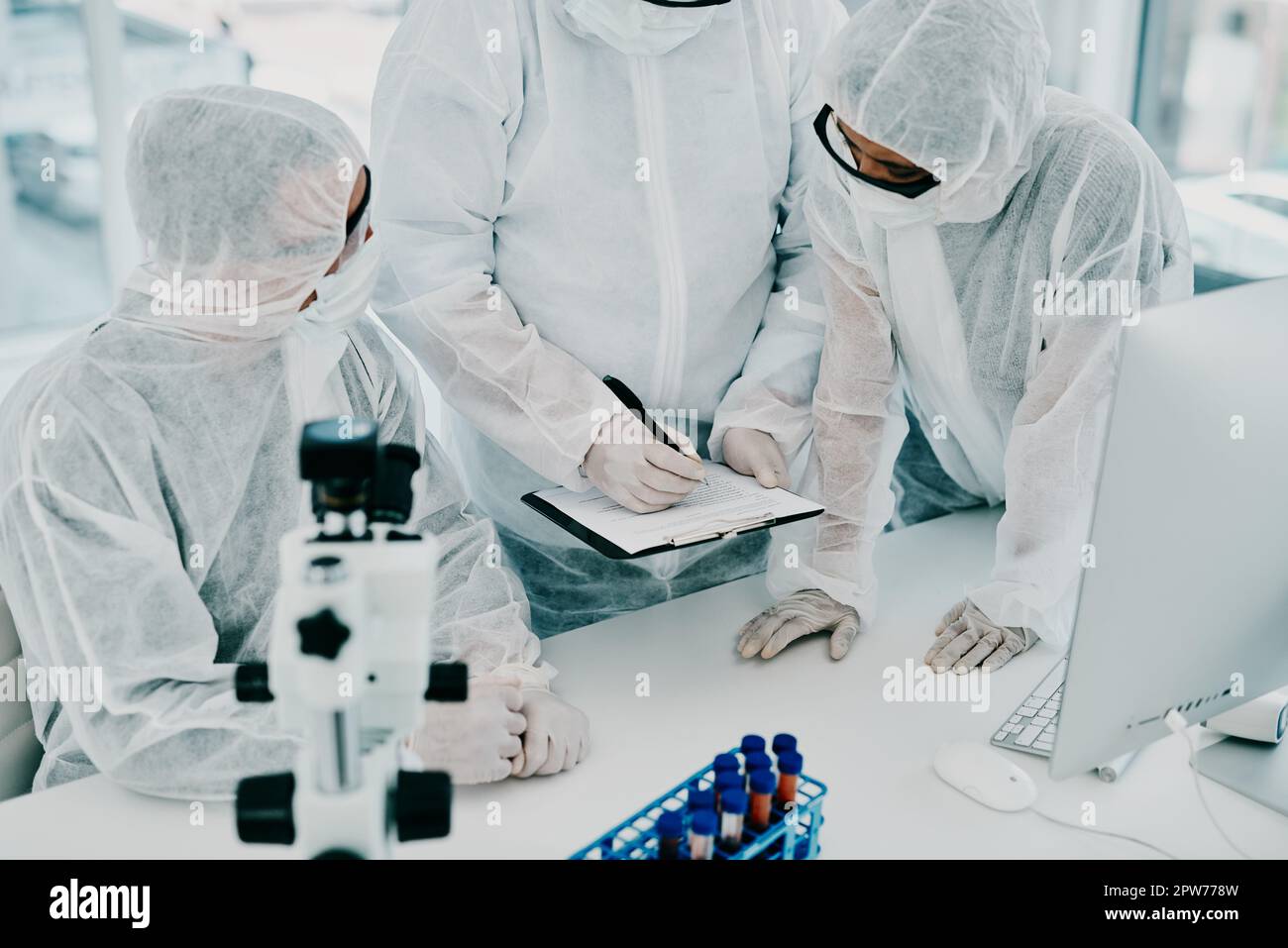 Team of scientists, pathologists and doctors in hazmat suits discussing ...