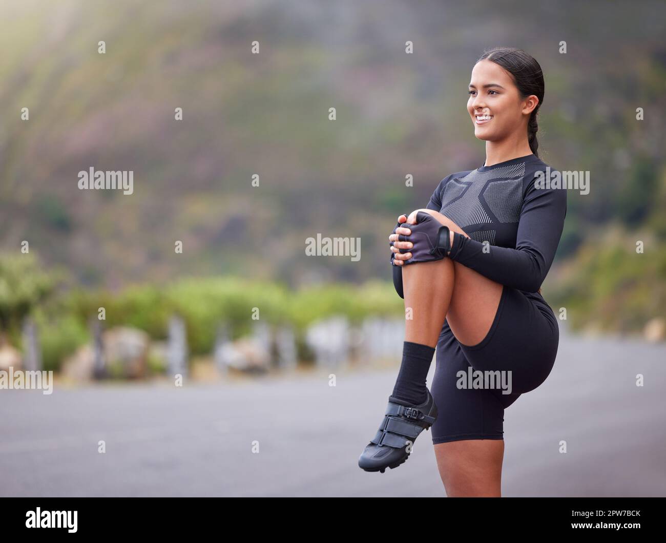Active and fit young mixed race woman stretching her leg during outdoor ...