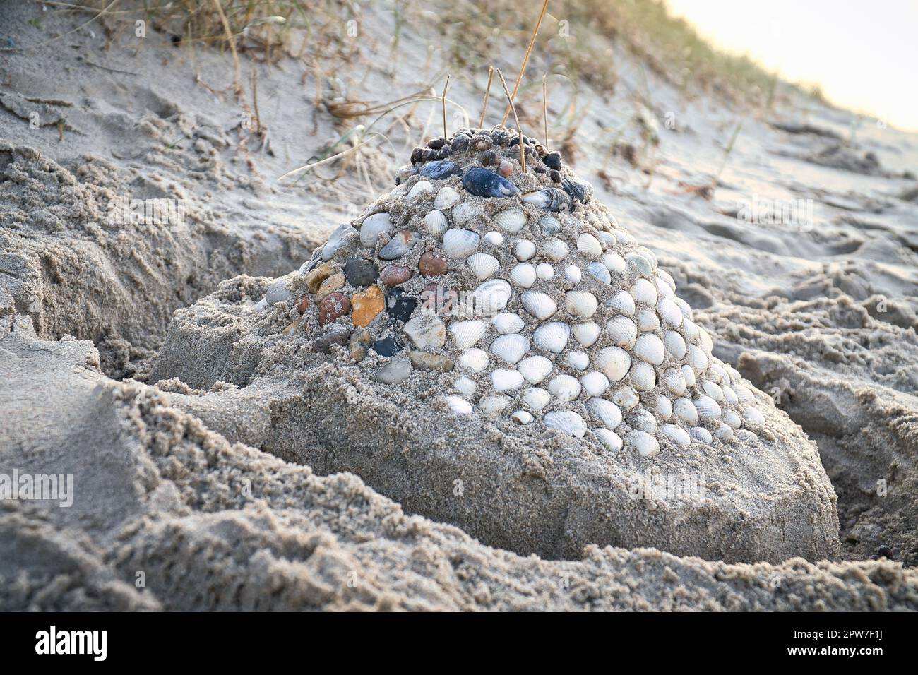 Sand castle with shells and sand. Moat around the castle in front of ...