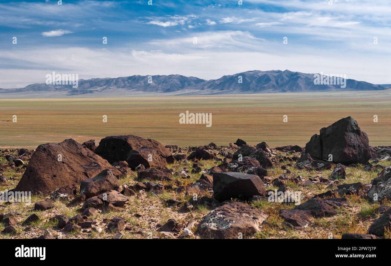 Steppe landscape with mountains in the background and stone boulders in the foreground in ...