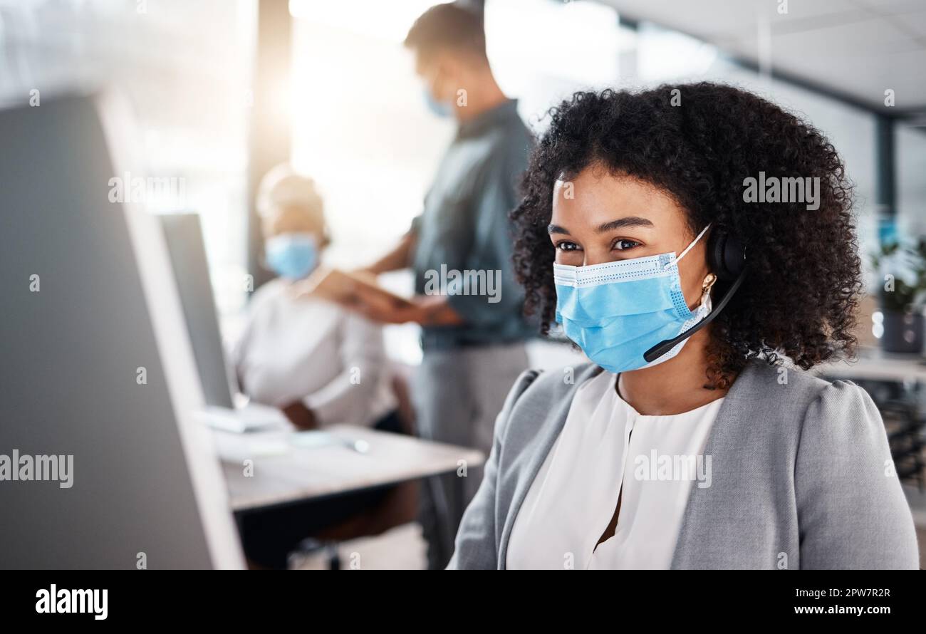 Mixed race call centre telemarketing agent wearing face mask as safety ...
