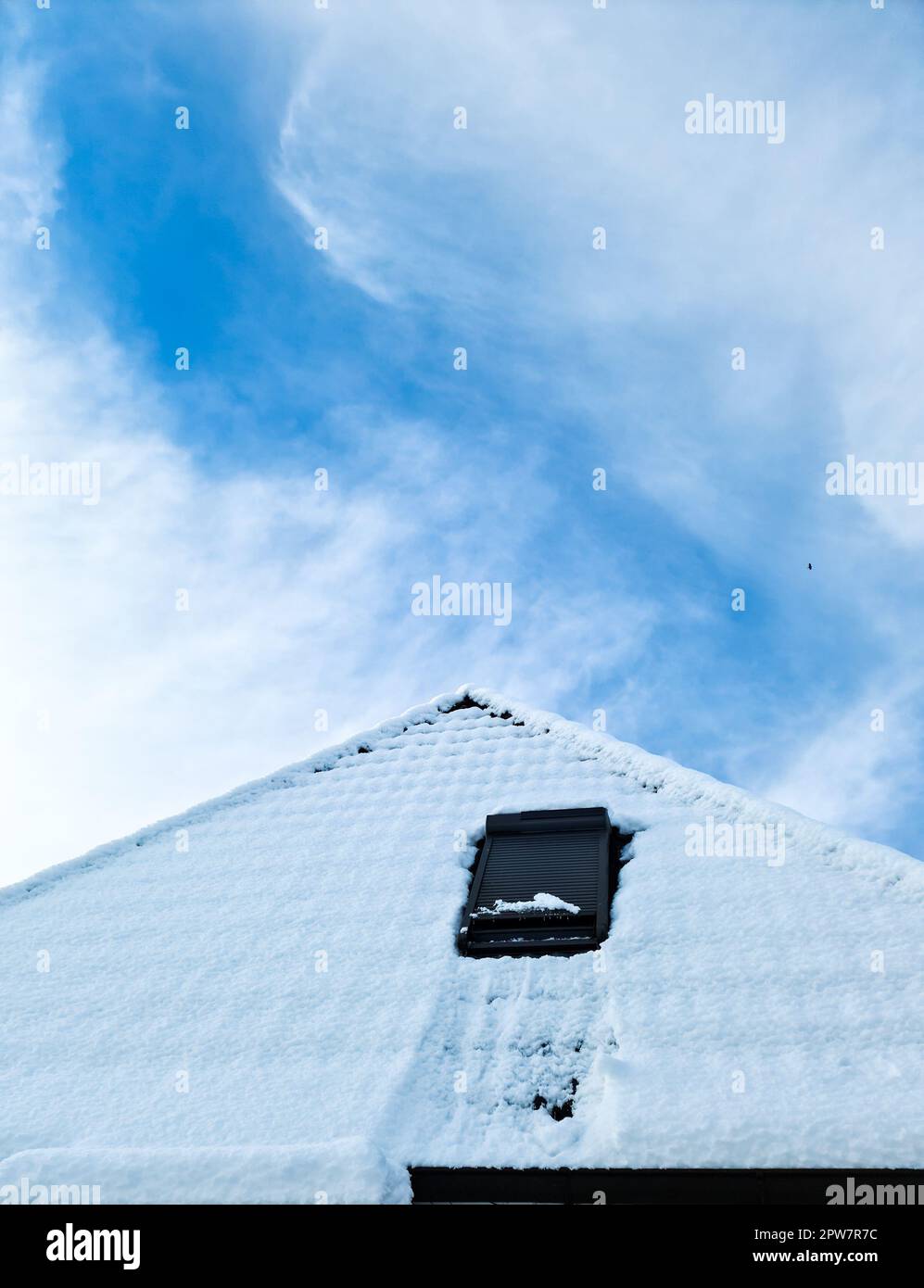 Open roof window in velux style with black roof tiles covered in snow ...