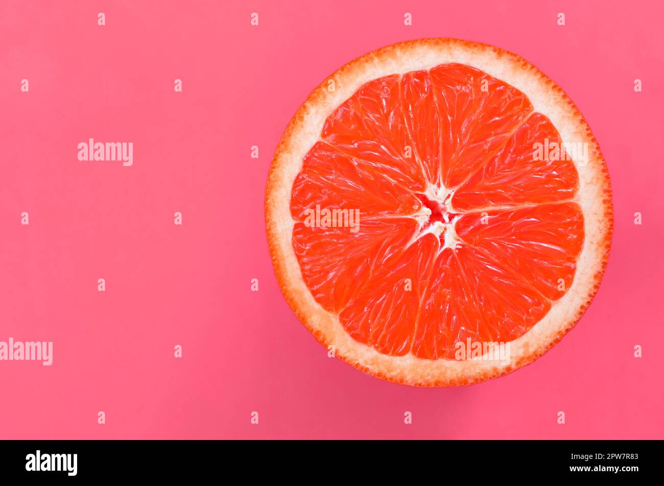 Top view of a one grapefruit slice on bright background in light pink ...
