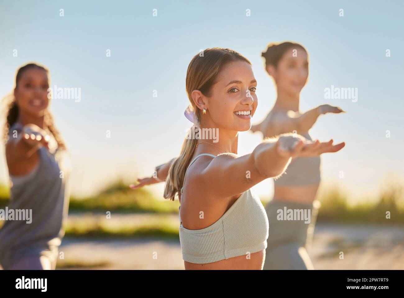 Diverse smiling yoga women in warrior pose during outdoor practice in ...