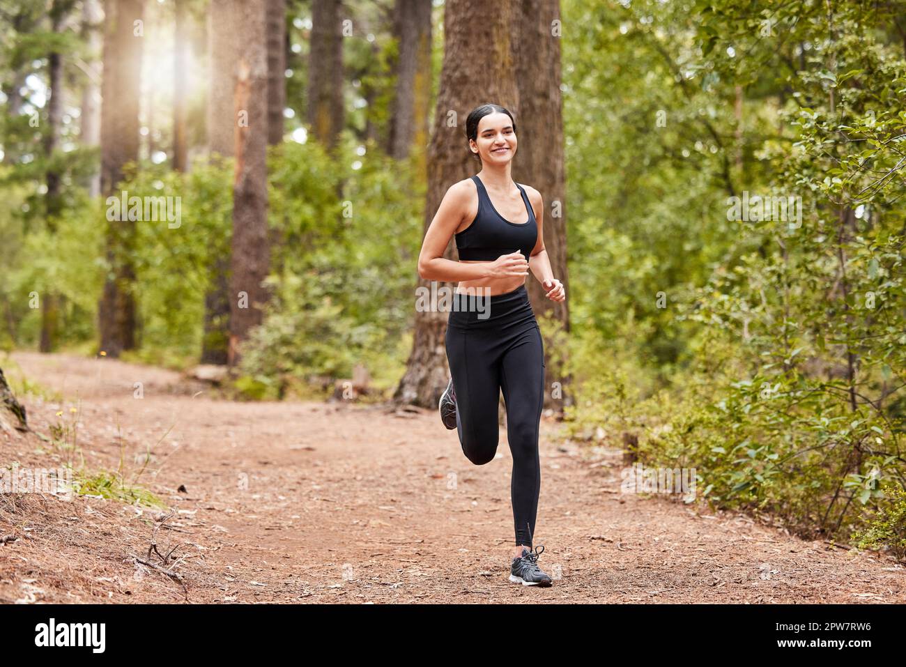 Young caucasian female athlete running outside in nature on the road ...