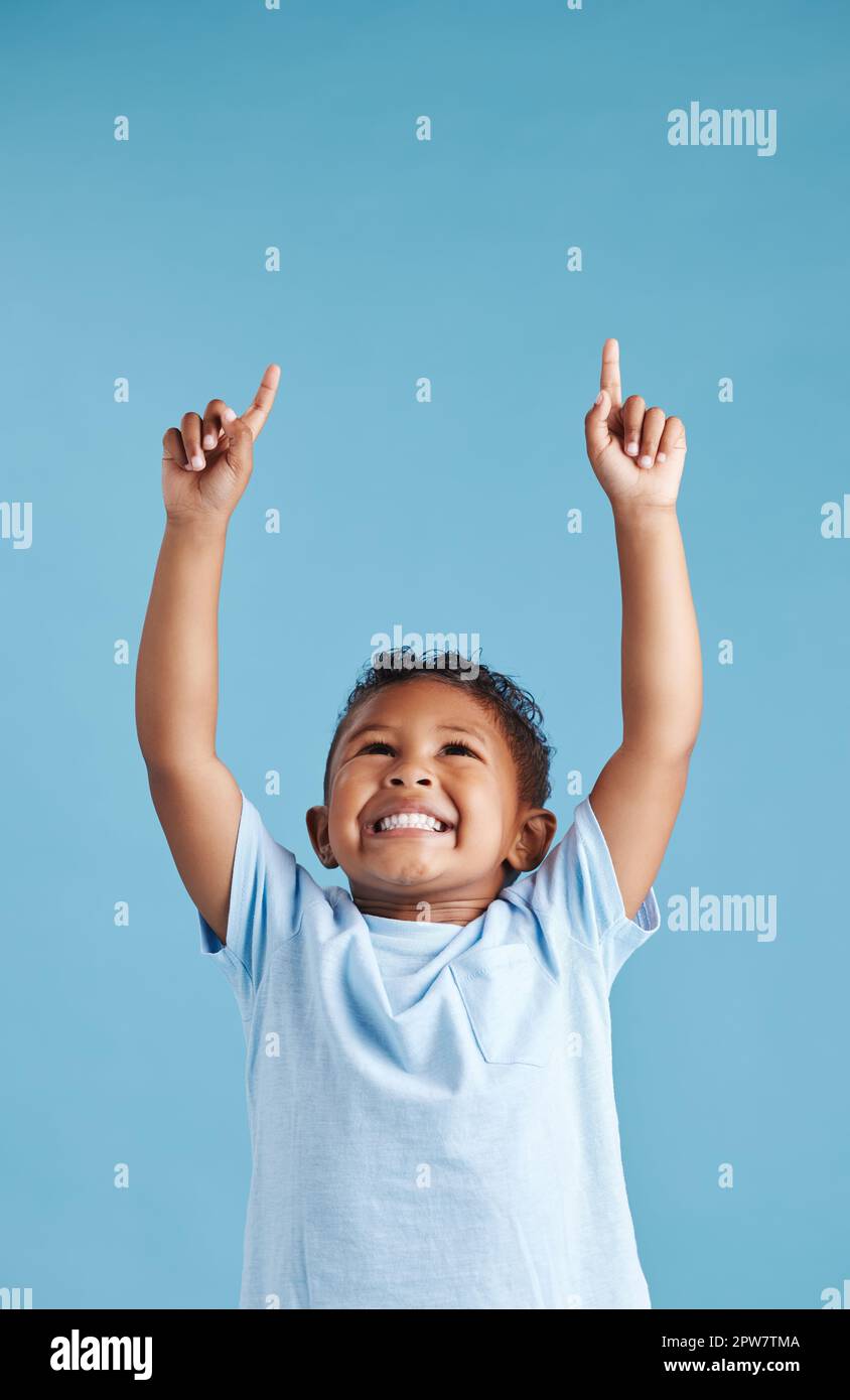 Excited little hispanic boy kid looking and pointing his fingers up at ...