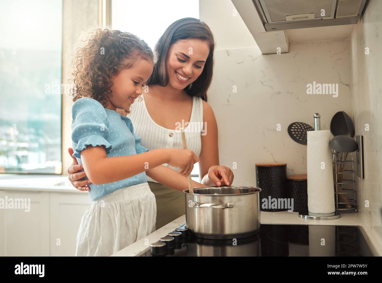Adorable little girl and her mother cooking together at home. Young ...