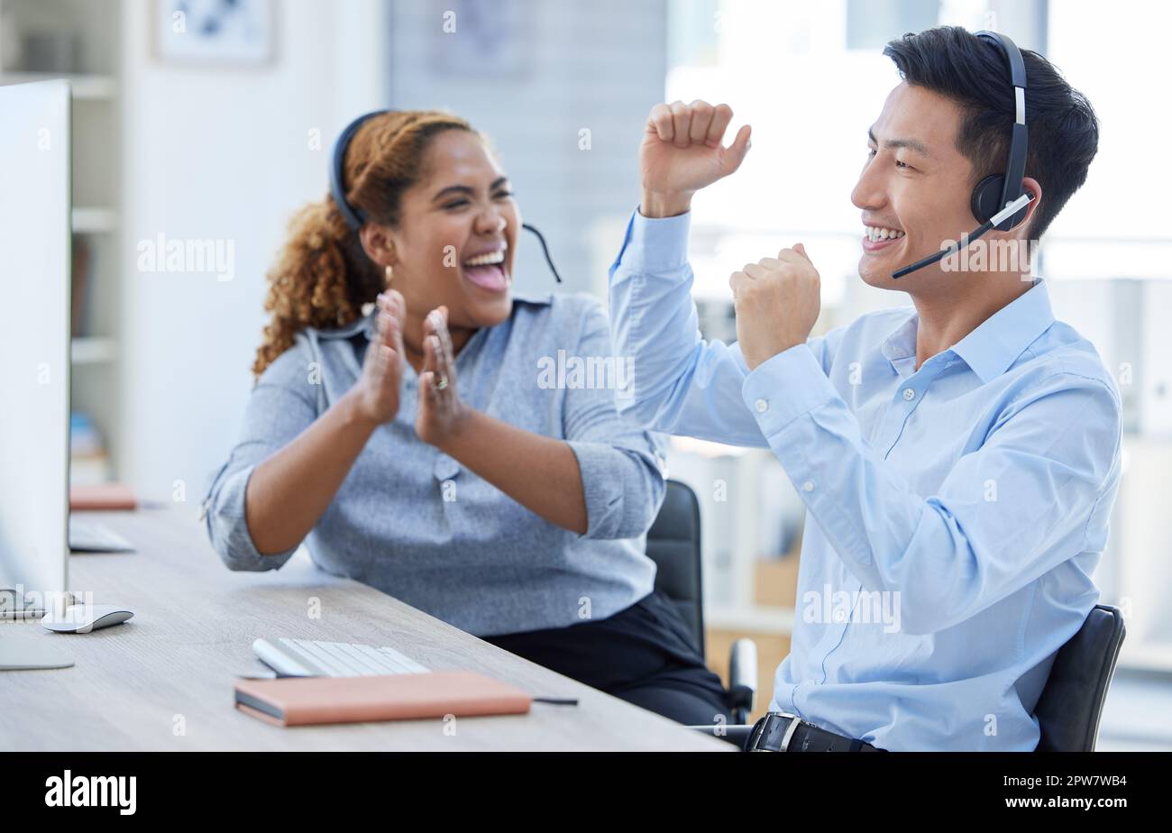 Two happy young call centre telemarketing agents clapping and cheering ...