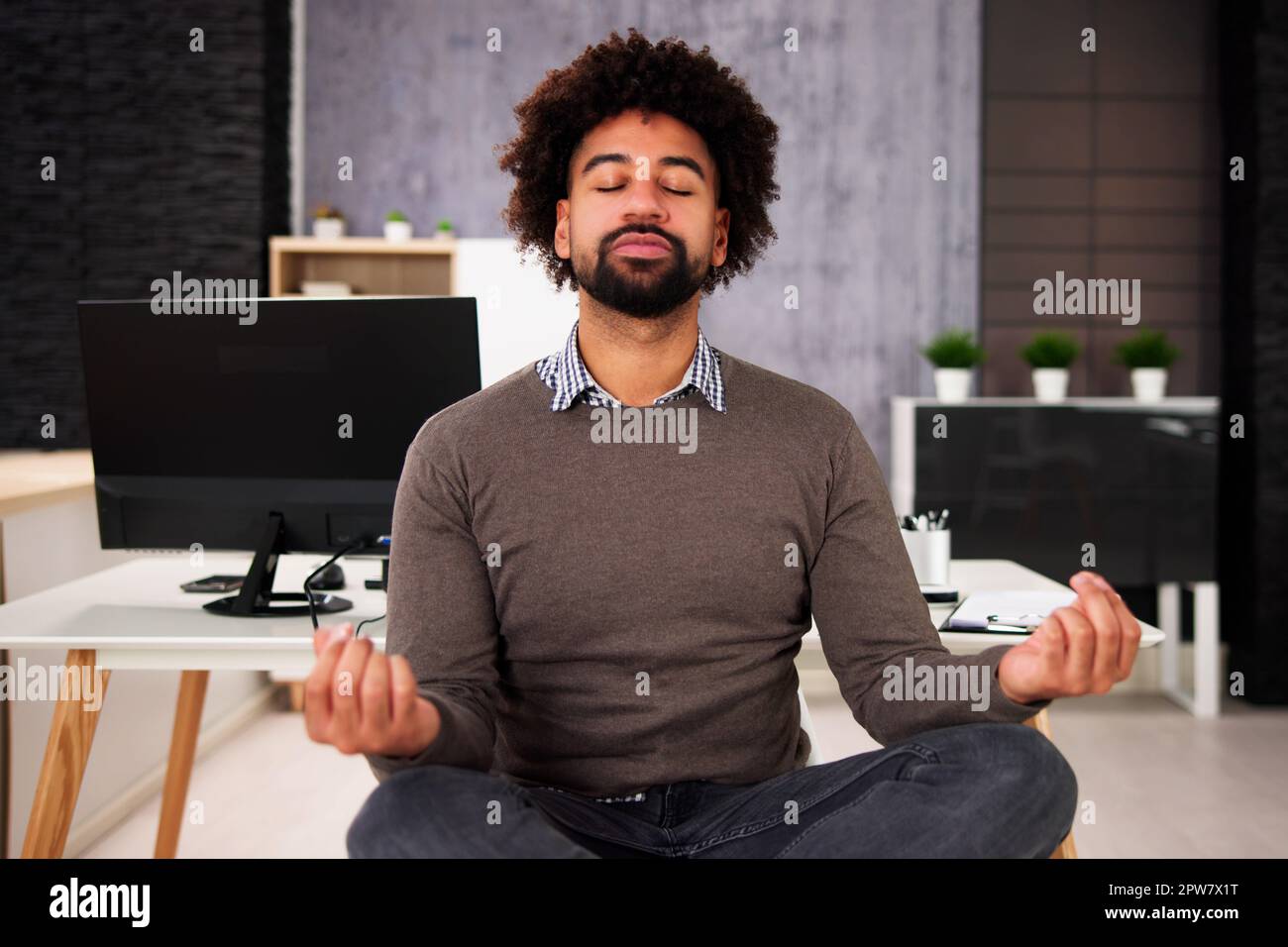 African American Male Meditation In Office Near Computer Stock Photo ...