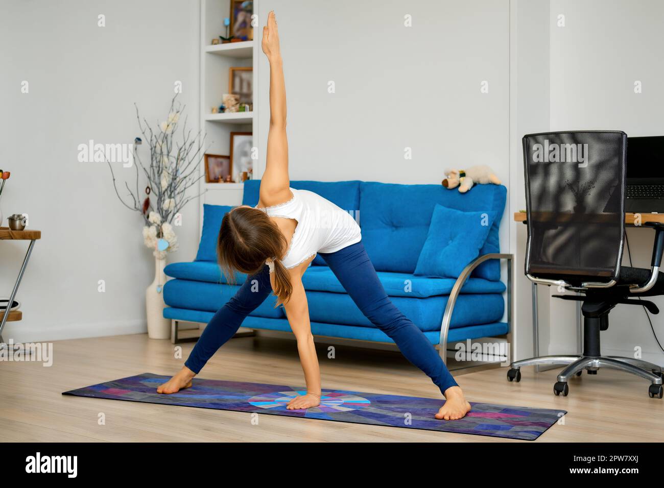 Full length portrait of young woman practicing yoga at home, standing ...
