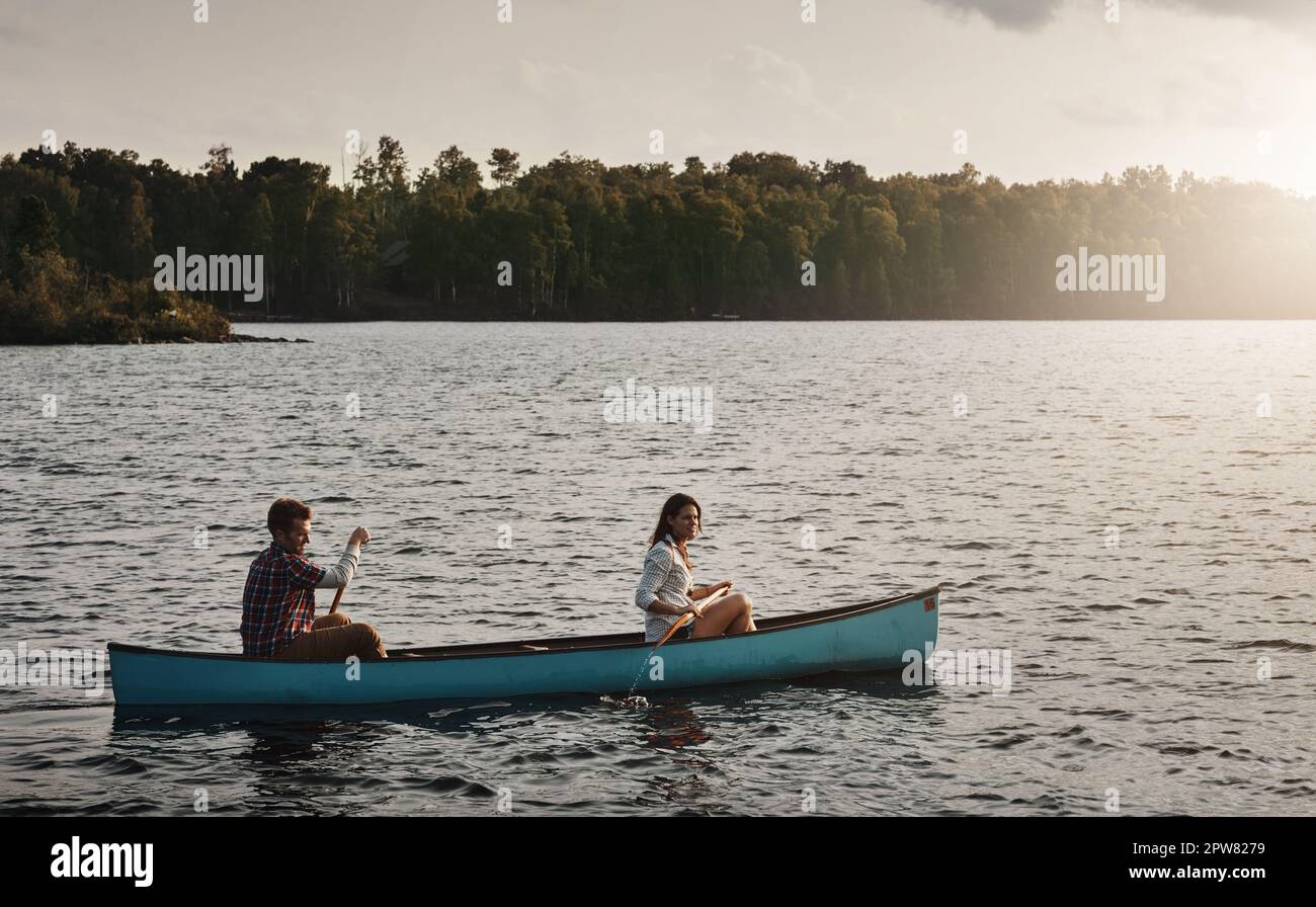 Enjoying the beauty in nature. a young couple rowing a boat out on the ...