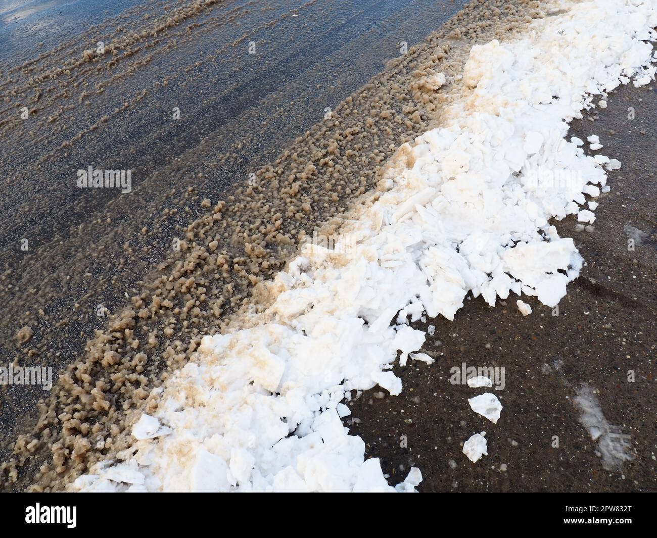 Roadside with a snowdrift. Difficult driving conditions. Wet slippery ...