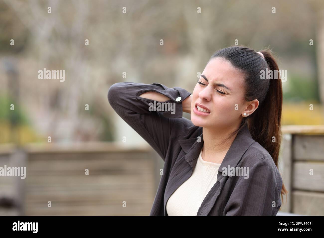 Teen complaining in a park suffering neck ache Stock Photo - Alamy