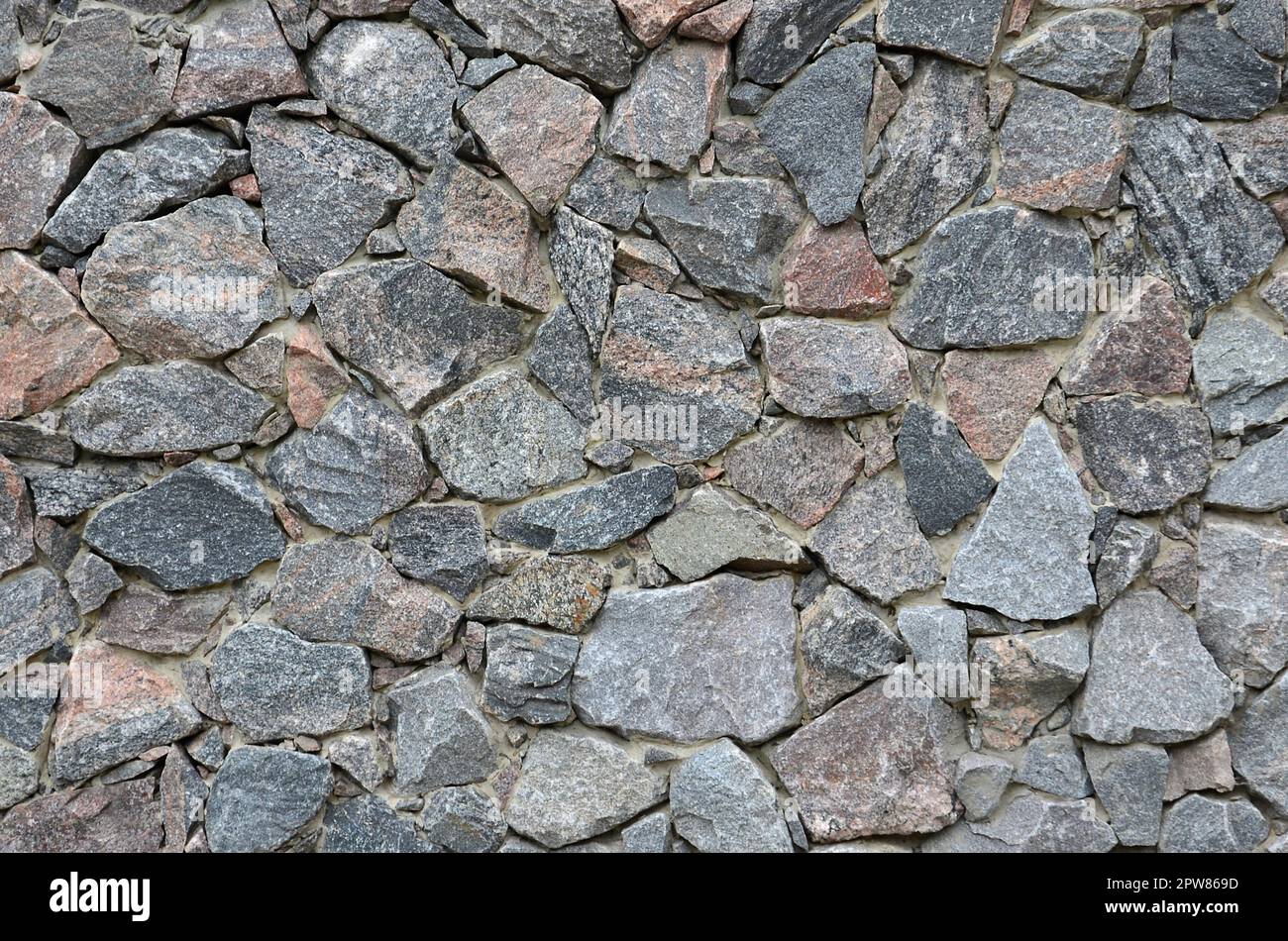 The texture of a strong stone wall of many concreted stones of various ...