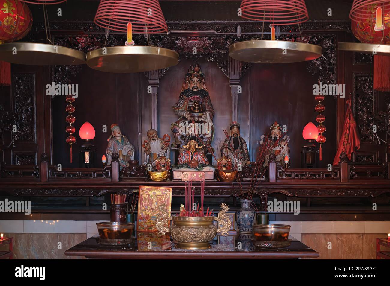 Indoor shrine with several Chinese Gods statues and candles surrounded ...