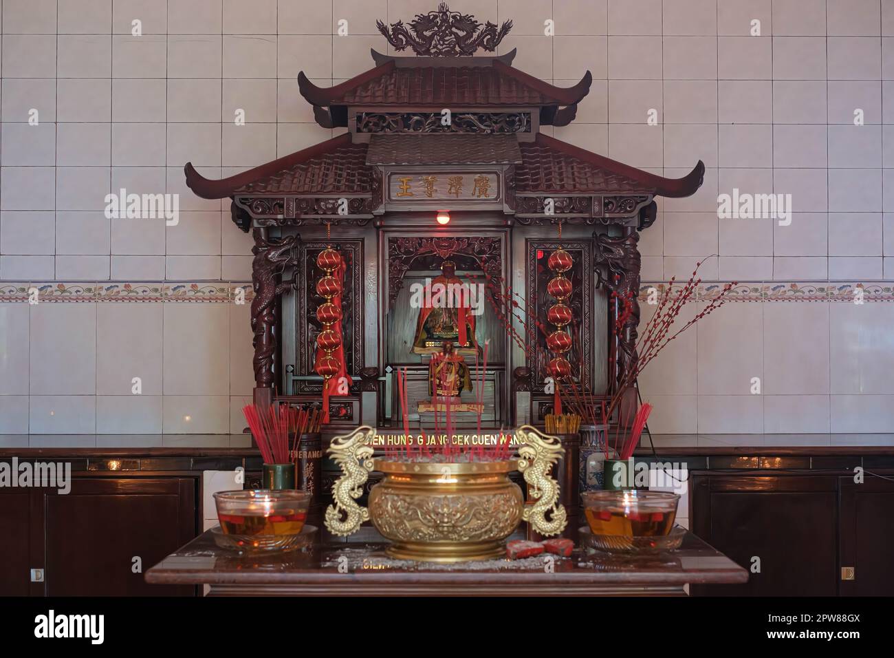 Indoor shrine with several Chinese Gods statues and candles surrounded ...