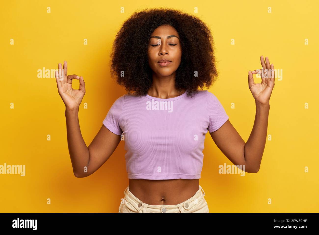 Portrait of relaxed dark skinned young lady with fluffy hair, makes ...