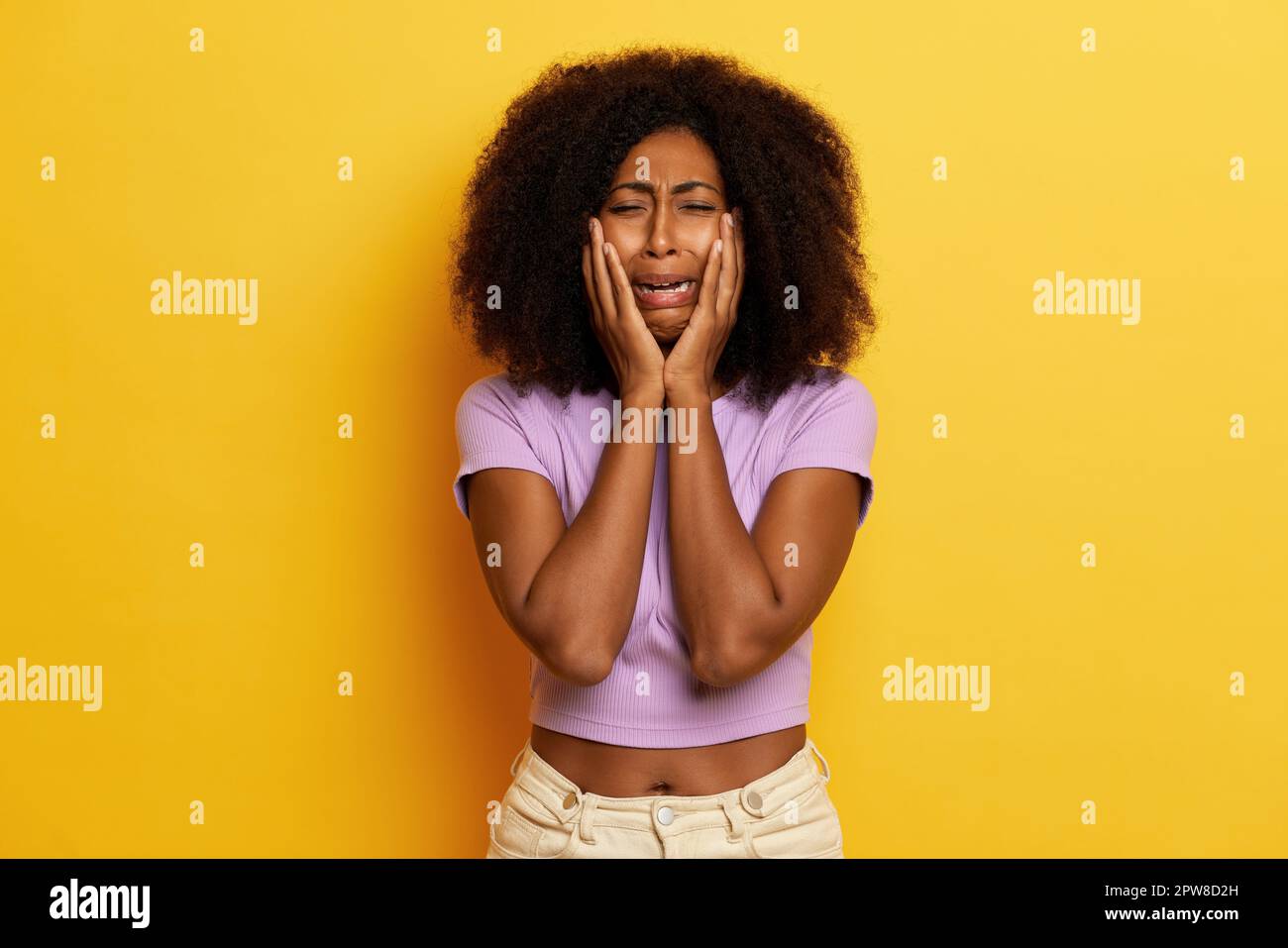 Distressed brunette girl cries and holds hands on a face, has a bad day ...
