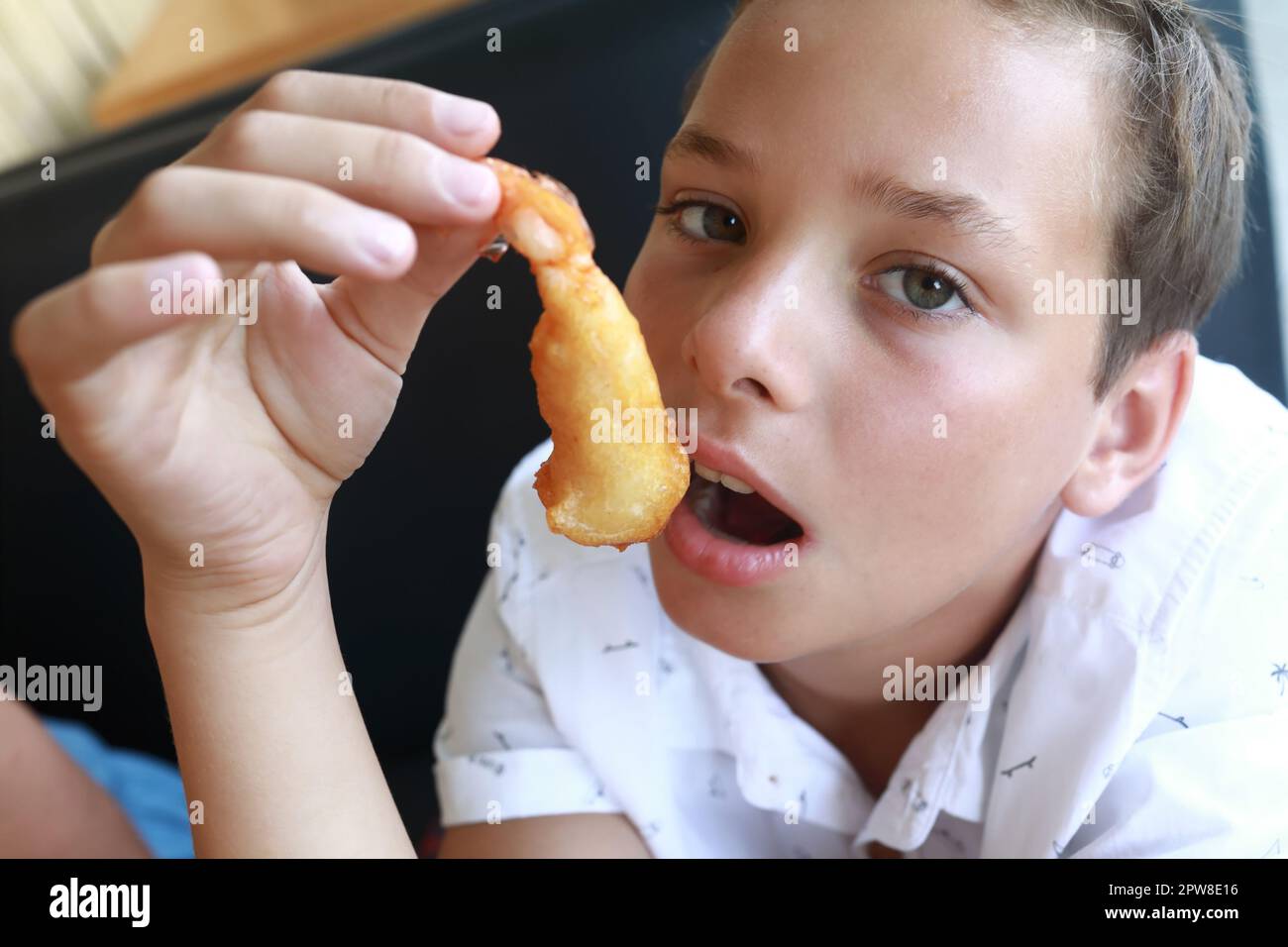 Boy biting battered shrimp in a restaurant Stock Photo - Alamy