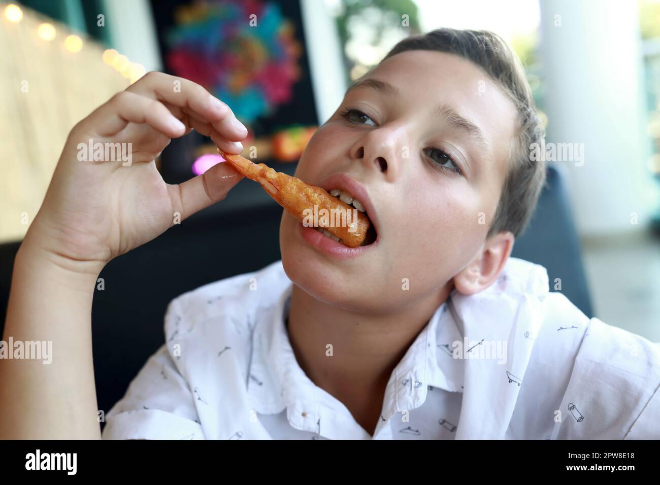 Boy eating battered shrimp in a restaurant Stock Photo - Alamy
