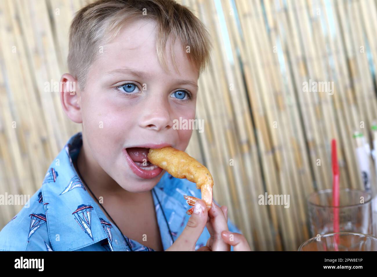 Child biting battered shrimp in a restaurant Stock Photo - Alamy