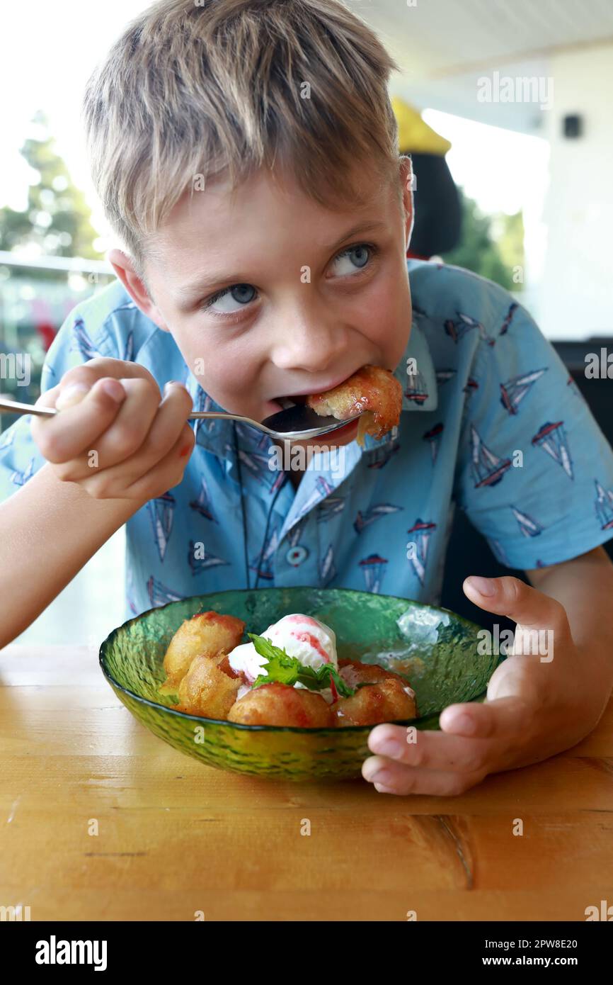 Child eating fried battered bananas in restaurant Stock Photo - Alamy