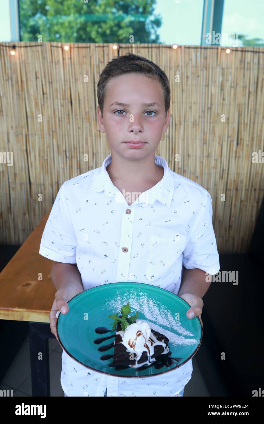 Child holding plate with brownie dessert in restaurant Stock Photo - Alamy