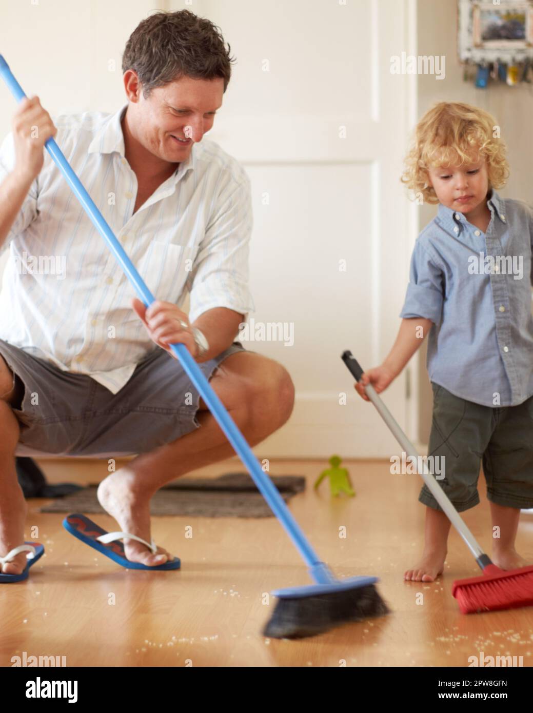Man is cleaning with boy kid, sweeping with broom and help with mess on ...