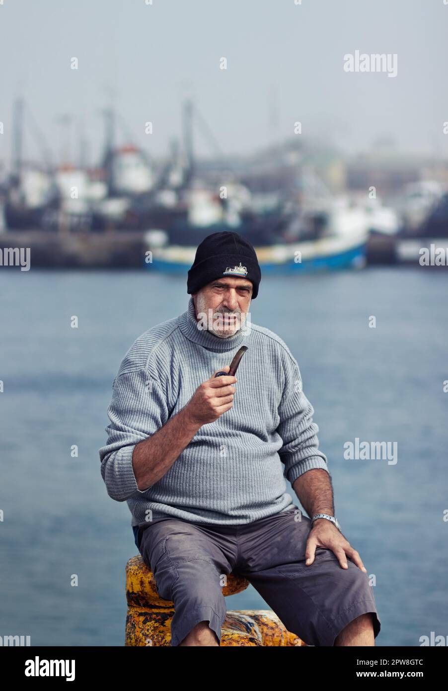 Fisherman, mature man portrait and smoking pipe by the sea water at a ...
