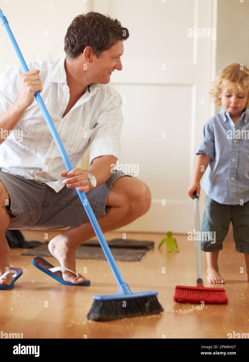 Man is cleaning with boy child, sweeping with broom and help with mess ...