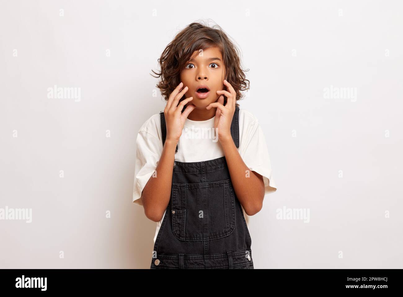 dumbfounded young dark-skinned guy with curly hair, dressed in overalls ...
