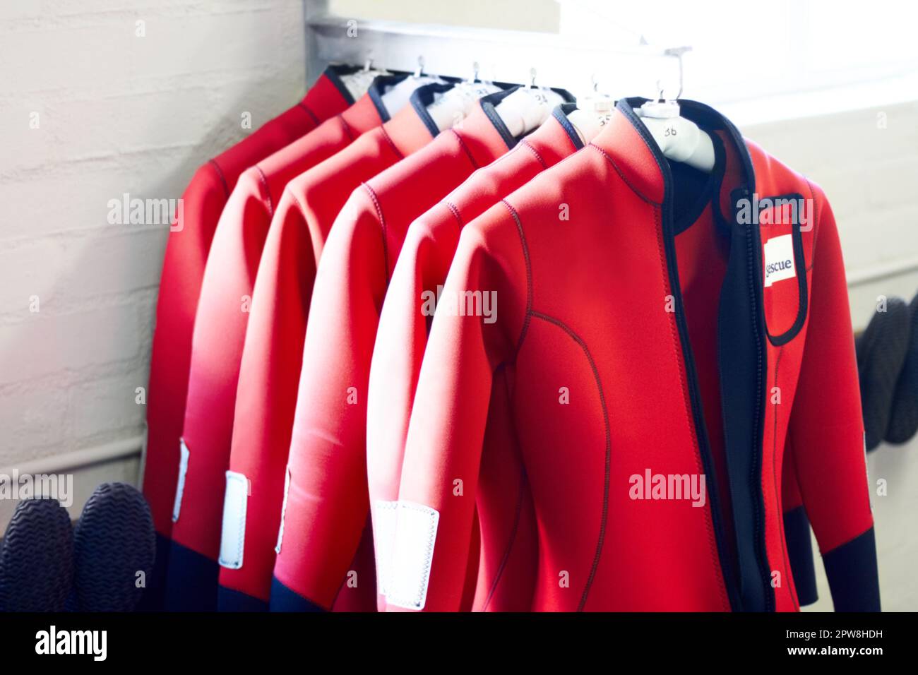 Safety, sea and wetsuits of life guard on hanger for emergency ...