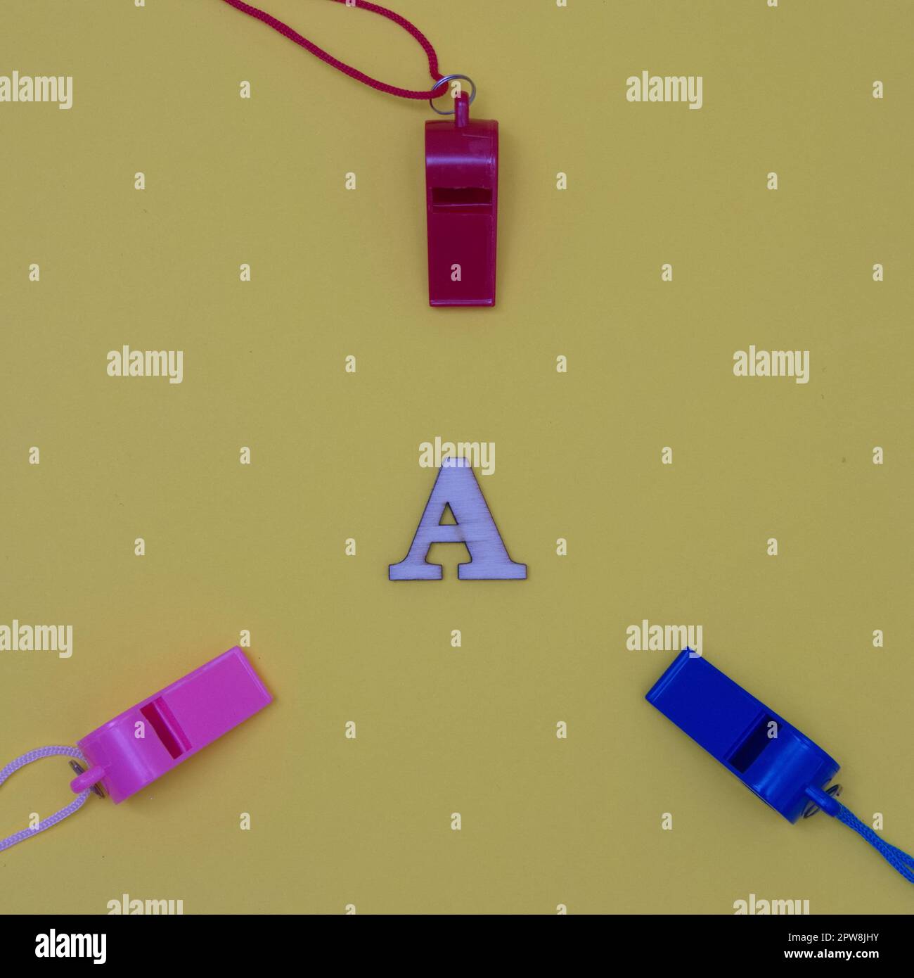 Three whistles of different colors arranged around the letter A on a ...