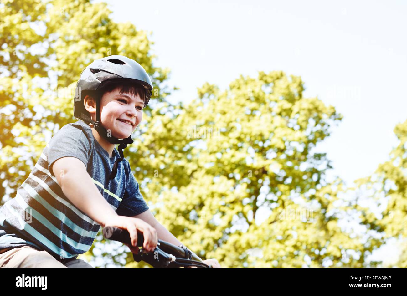 Its important for kids to stay active. a young boy riding his bicycle ...